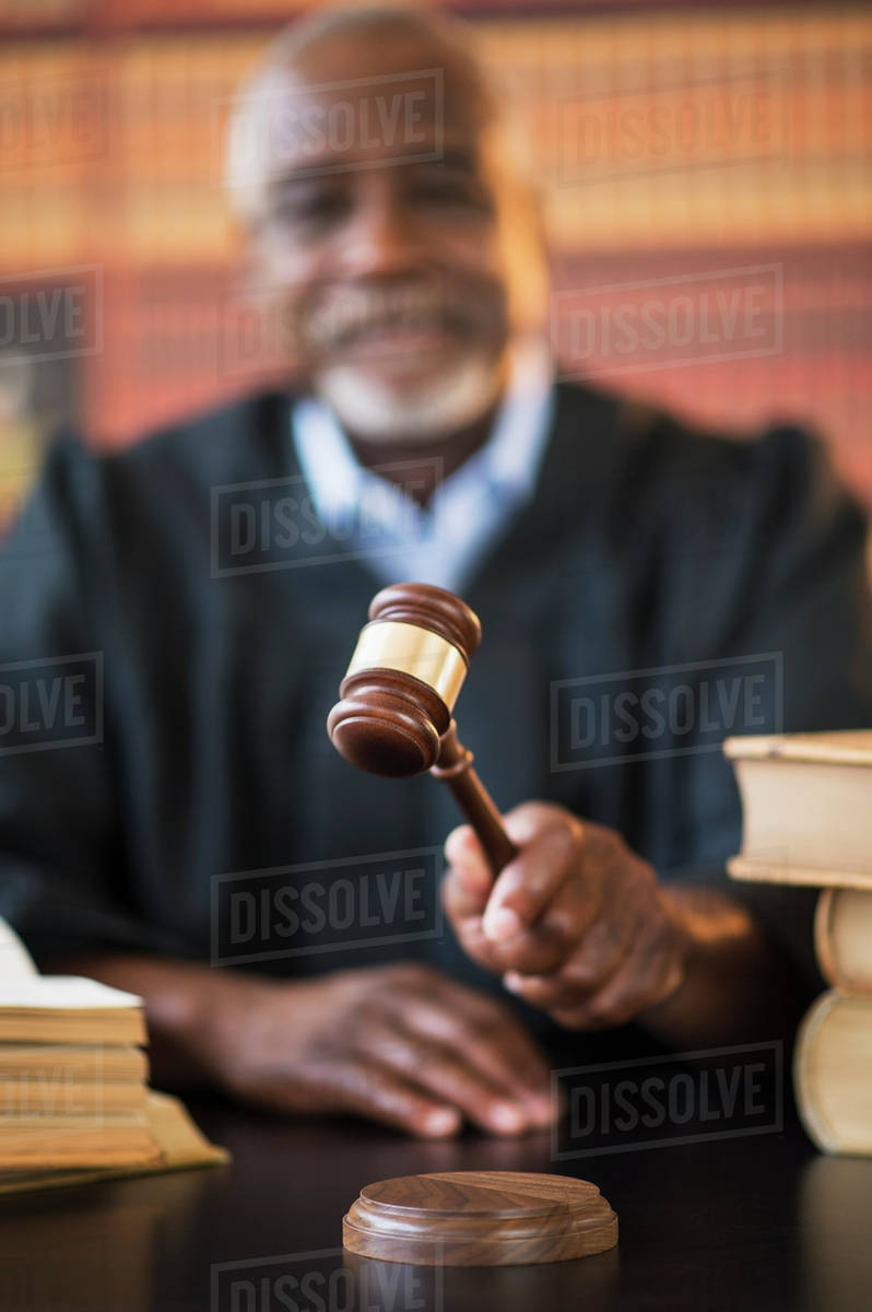 Judge holding gavel in courtroom - Stock Photo - Dissolve