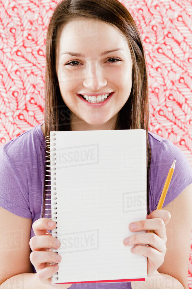 Portrait of smiling young woman holding blank notebook - Royalty-free ...