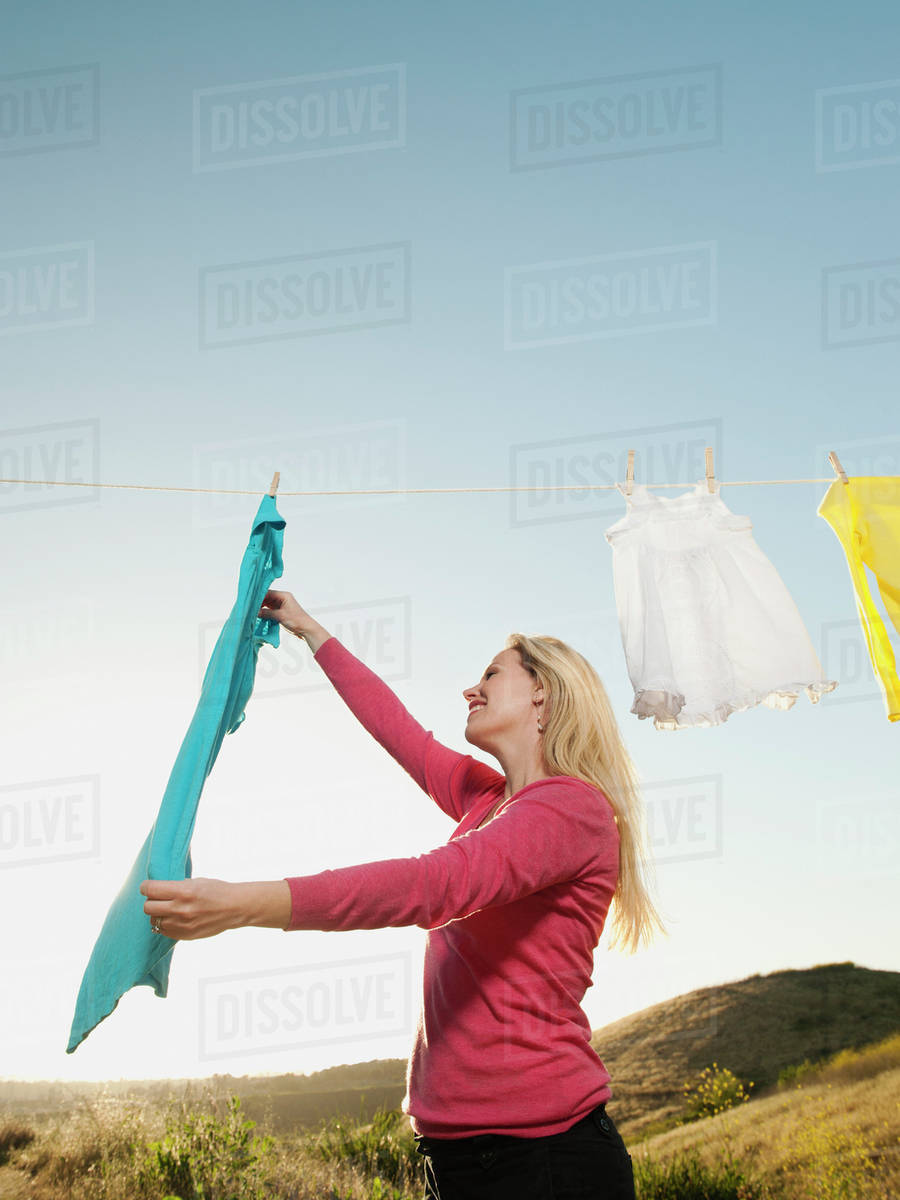 Woman hanging laundry on clothesline - Stock Photo - Dissolve