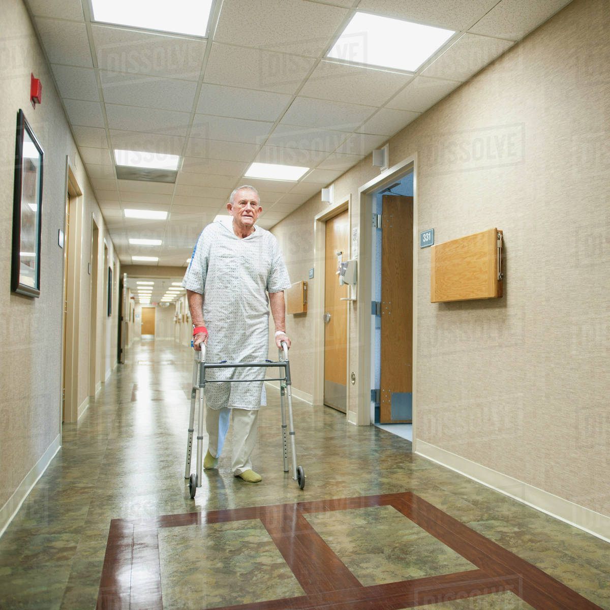 Senior man in hospital walking with walker - Stock Photo - Dissolve