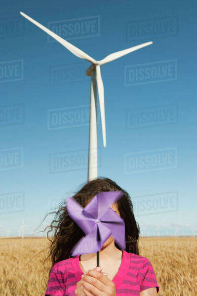 USA, Oregon, Wasco, Girl (12-13) holding fan n front of wind turbines ...
