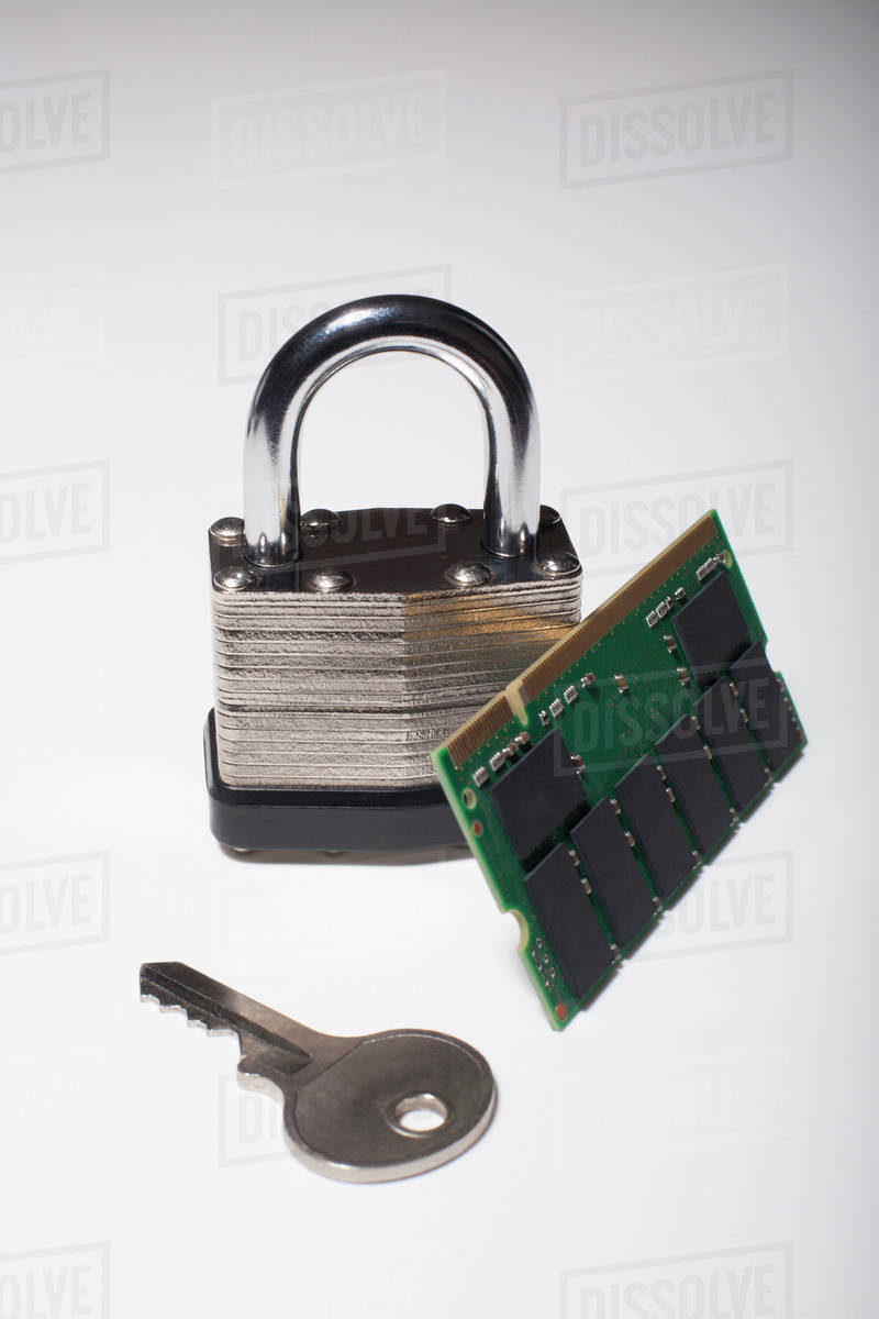 Close-up studio shot of silver padlock with key and computer chip ...