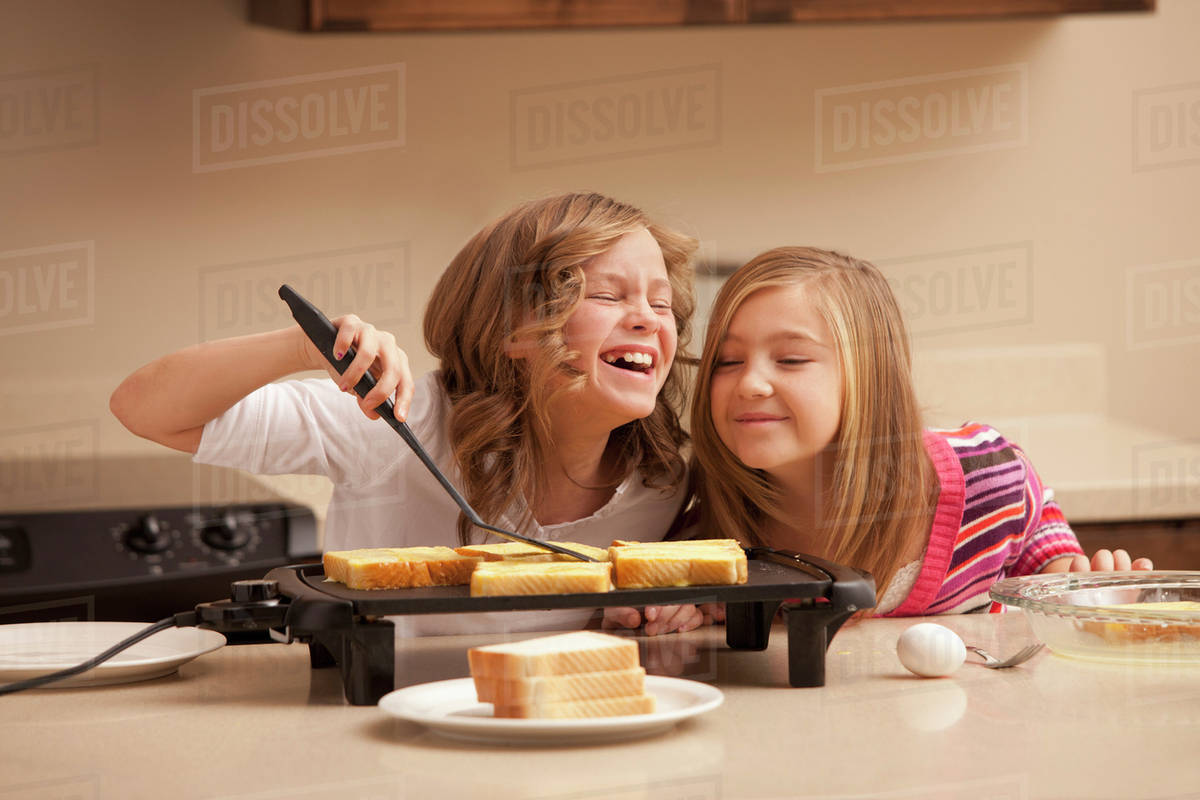 Two girls (10-11) preparing toast in kitchen - Royalty-free Stock Photo ...