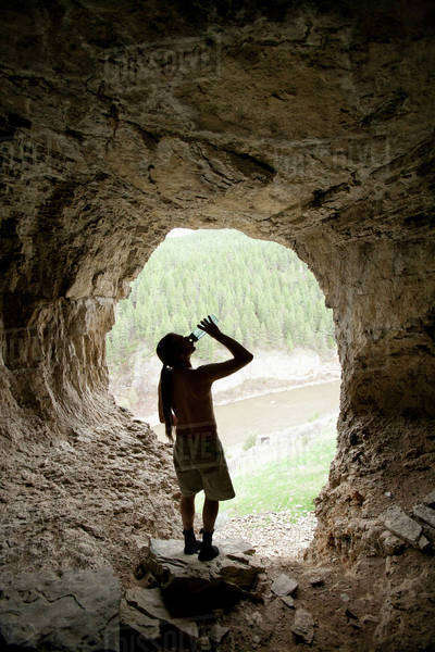 USA, Montana, Smith River, Young man drinking water in cave - Royalty ...