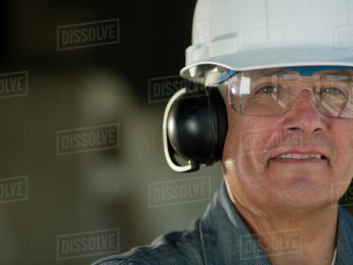 Portrait of industrial worker wearing hard hat and ear protectors ...