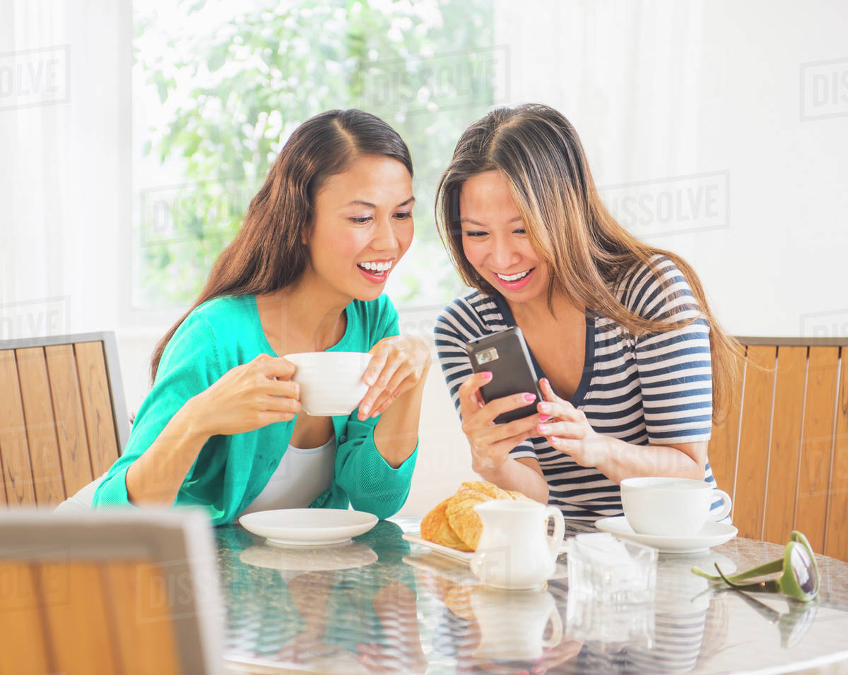 Two women using mobile phone - Royalty-free Stock Photo | Dissolve