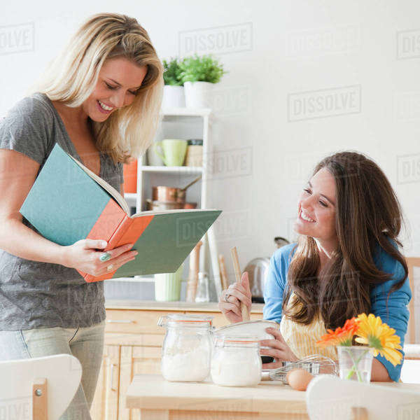 Woman reading book in kitchen - Royalty-free Stock Photo | Dissolve