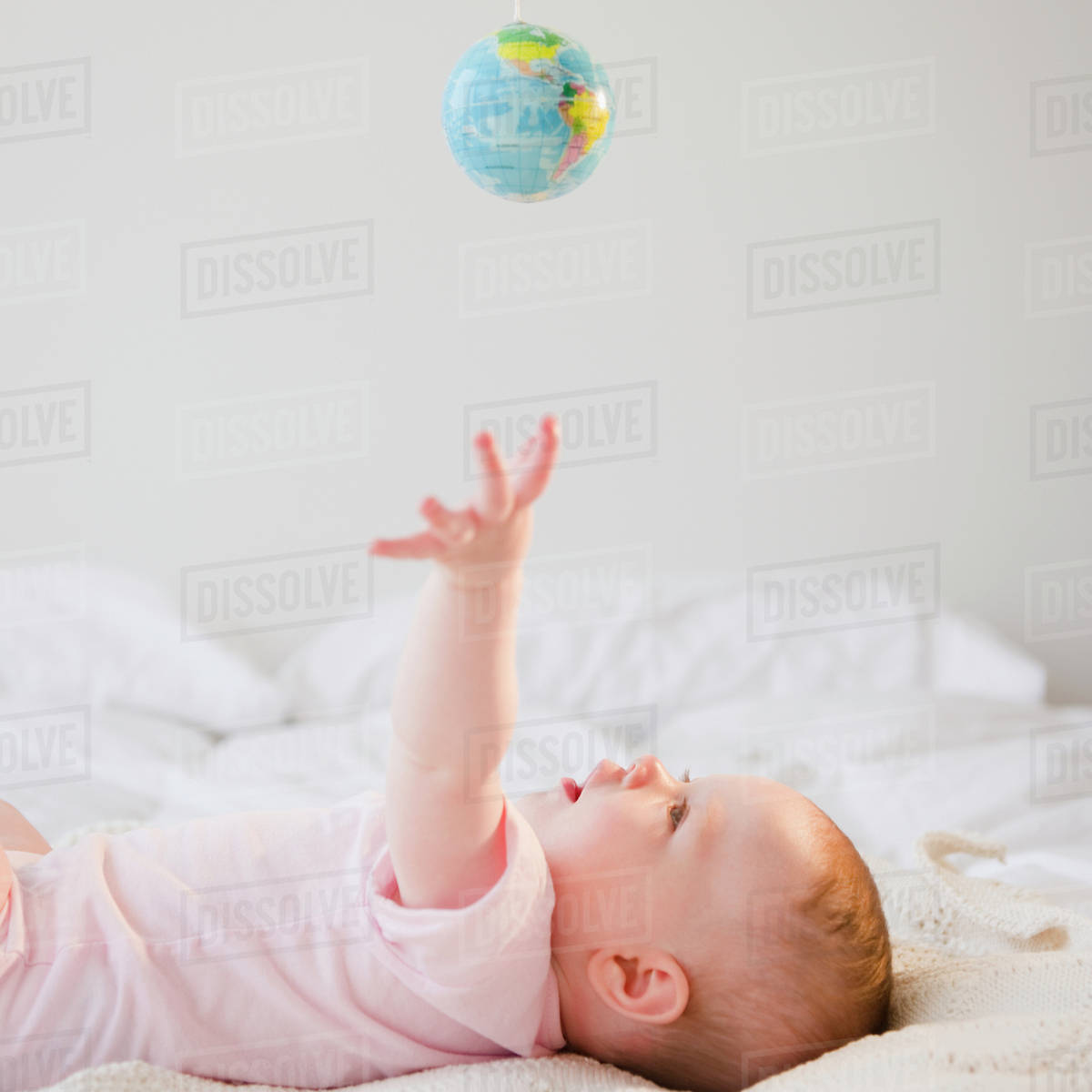 Baby reaching for globe - Stock Photo - Dissolve