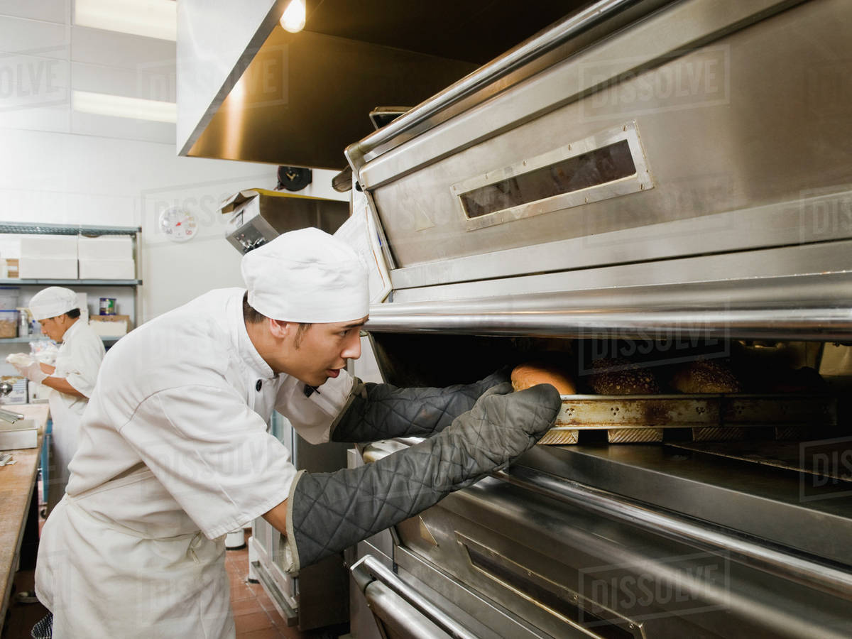 Chef putting bread in oven - Royalty-free Stock Photo | Dissolve