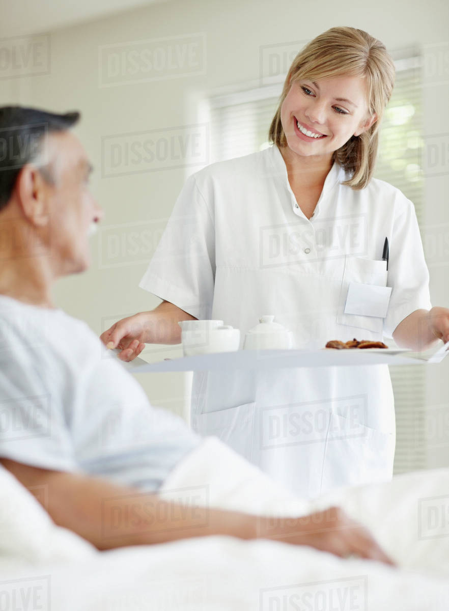 Nurse giving tray of food to patient - Stock Photo - Dissolve