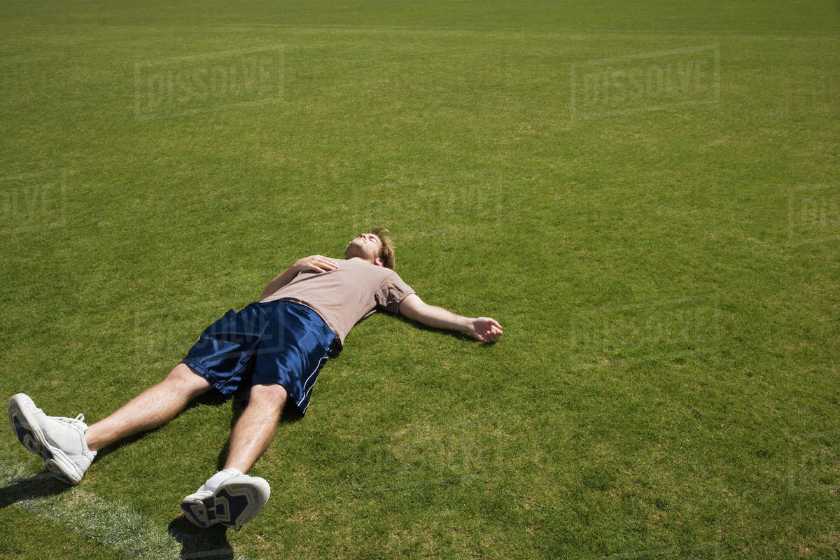 Defeated athlete lying on grass - Royalty-free Stock Photo | Dissolve