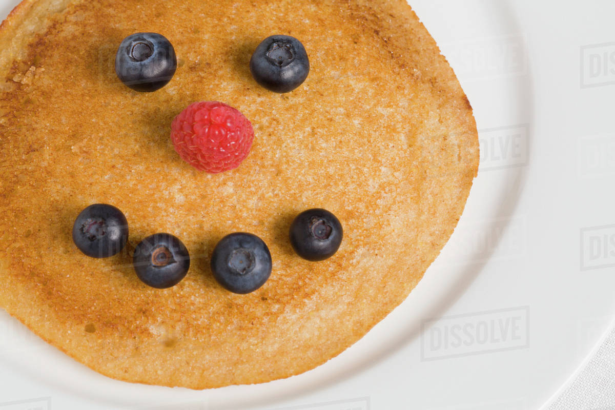 Pancake with smiley face made from blueberries and raspberry - Stock ...