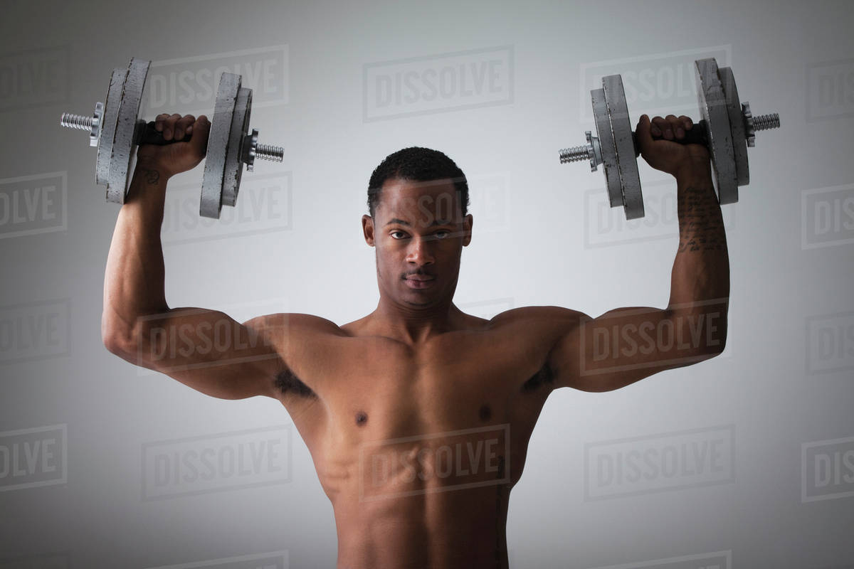 Muscular man lifting dumbbells - Stock Photo - Dissolve