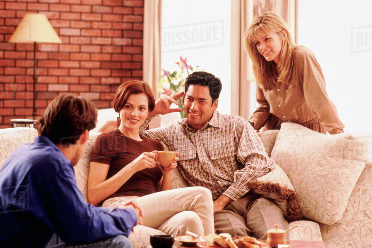 Four friends socializing in living room - Royalty-free Stock Photo ...