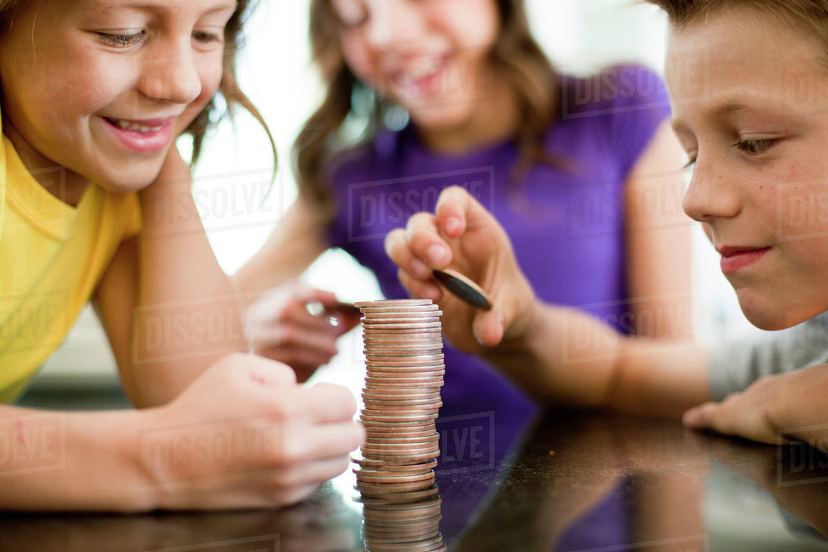 Children stacking coins - Royalty-free Stock Photo | Dissolve