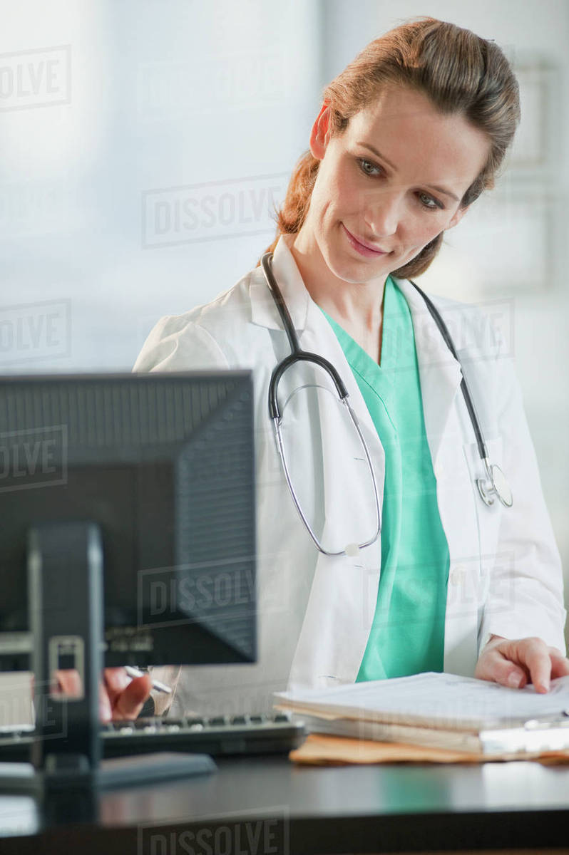 Female doctor looking at computer monitor - Royalty-free Stock Photo ...