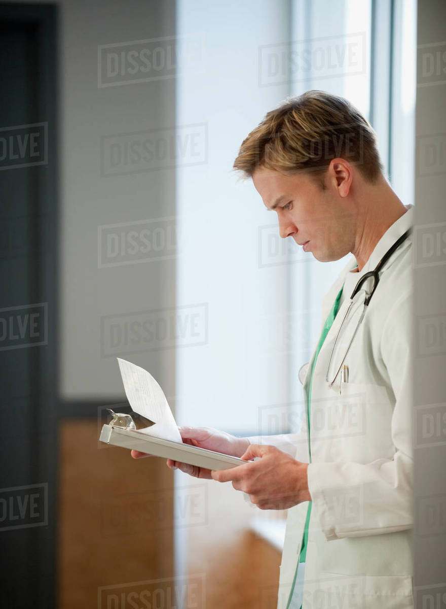 Doctor reading medical chart - Stock Photo - Dissolve