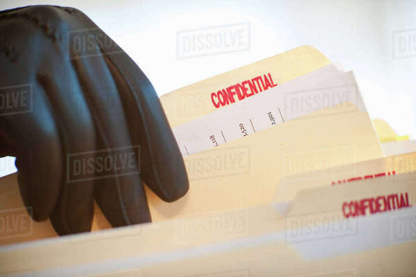 A gloved hand taking confidential files - Stock Photo - Dissolve