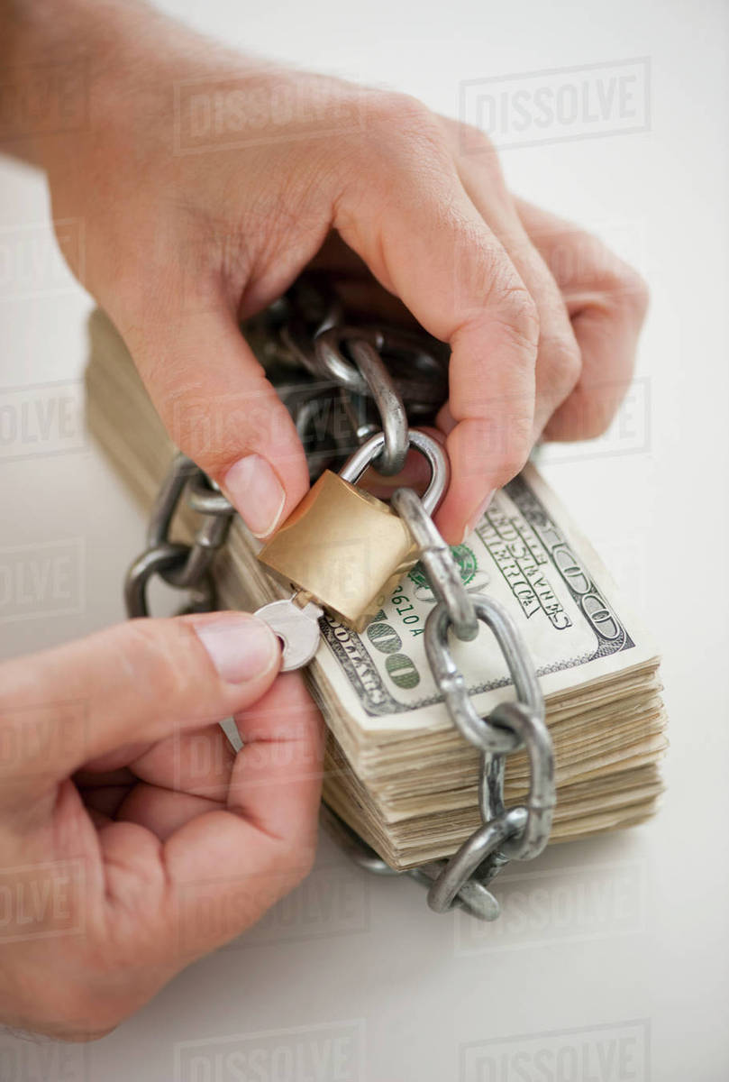Hands placing lock around money - Stock Photo - Dissolve
