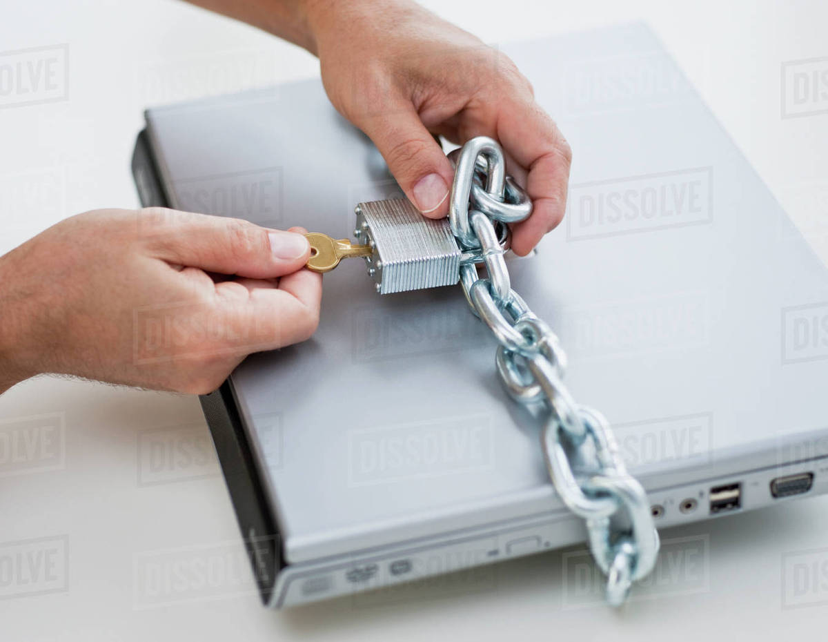 Hands placing lock and chain on computer - Stock Photo - Dissolve
