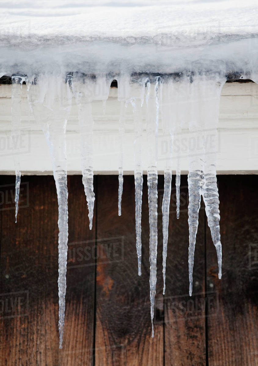 Icicles hanging from roof eaves - Royalty-free Stock Photo | Dissolve