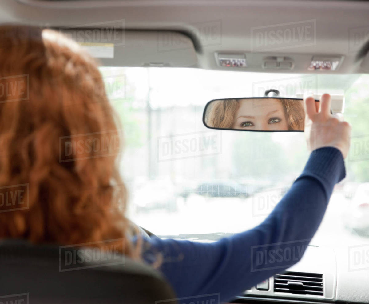 Woman adjusting driving mirror - Royalty-free Stock Photo | Dissolve