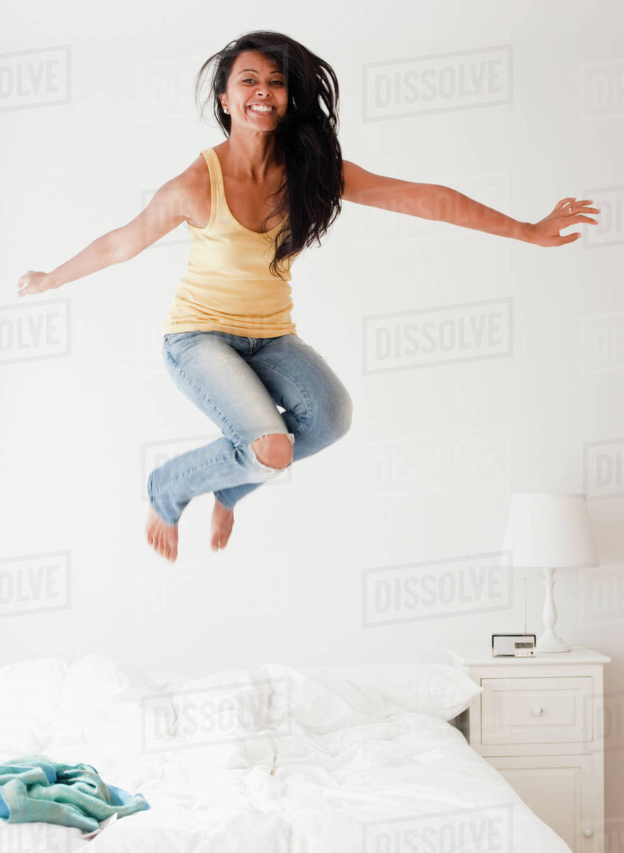 Woman jumping on bed - Royalty-free Stock Photo | Dissolve