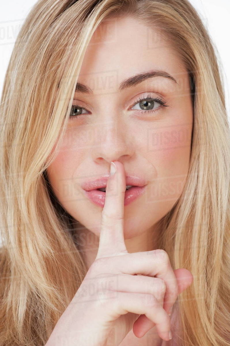 Studio portrait of young woman with finger to lips - Royalty-free Stock ...