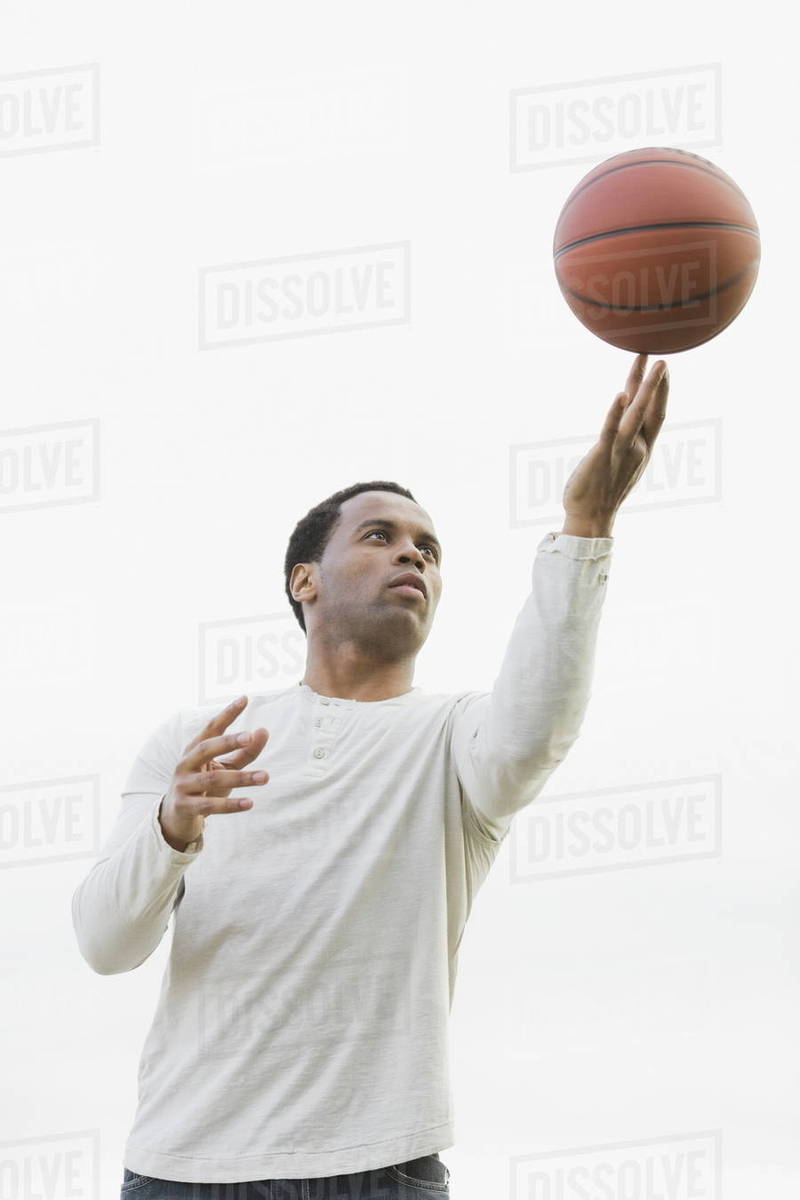 Man playing with basketball, studio shot - Stock Photo - Dissolve