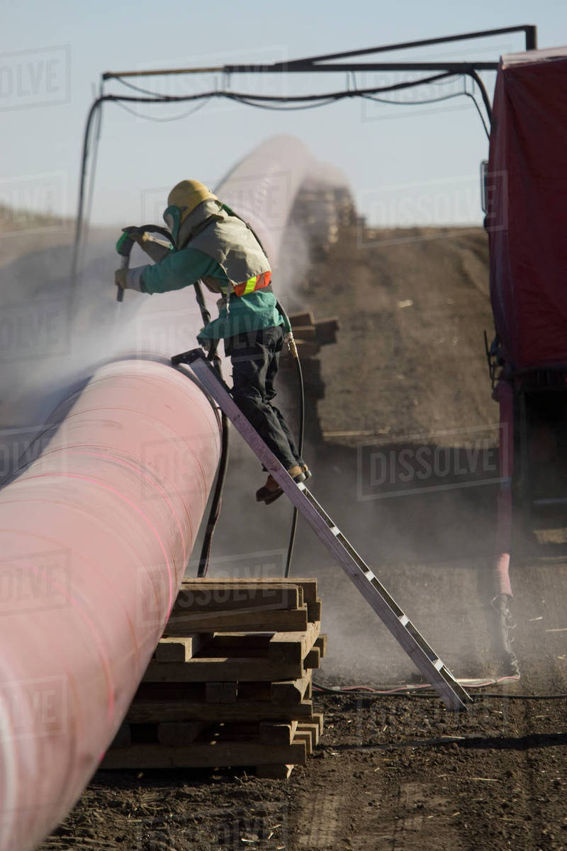 Construction worker cleaning pipeline - Royalty-free Stock Photo | Dissolve