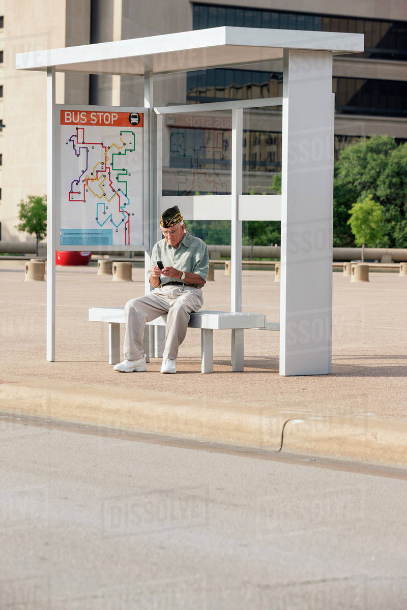 Senior man sitting at bus stop and text messaging - Royalty-free Stock ...