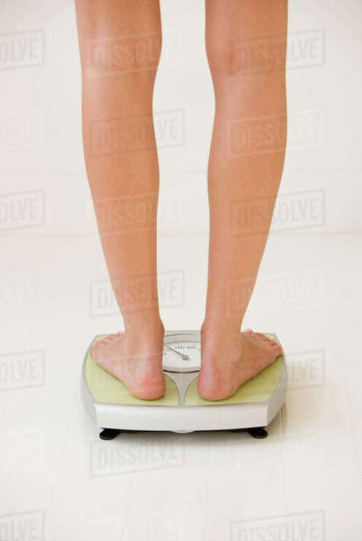 Woman standing on scale - Stock Photo - Dissolve