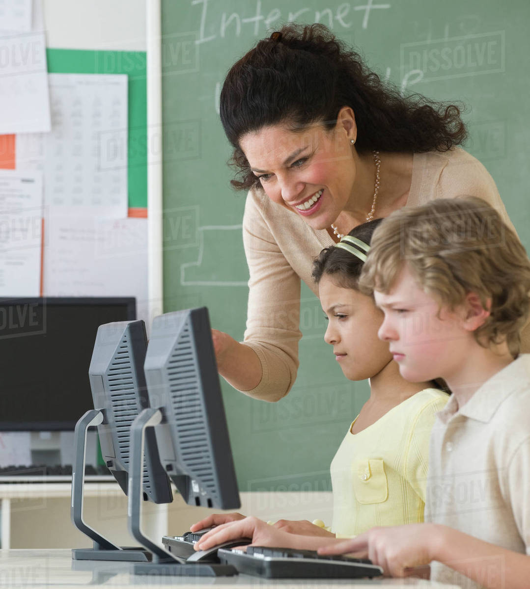 Hispanic teacher helping students with computers - Royalty-free Stock ...