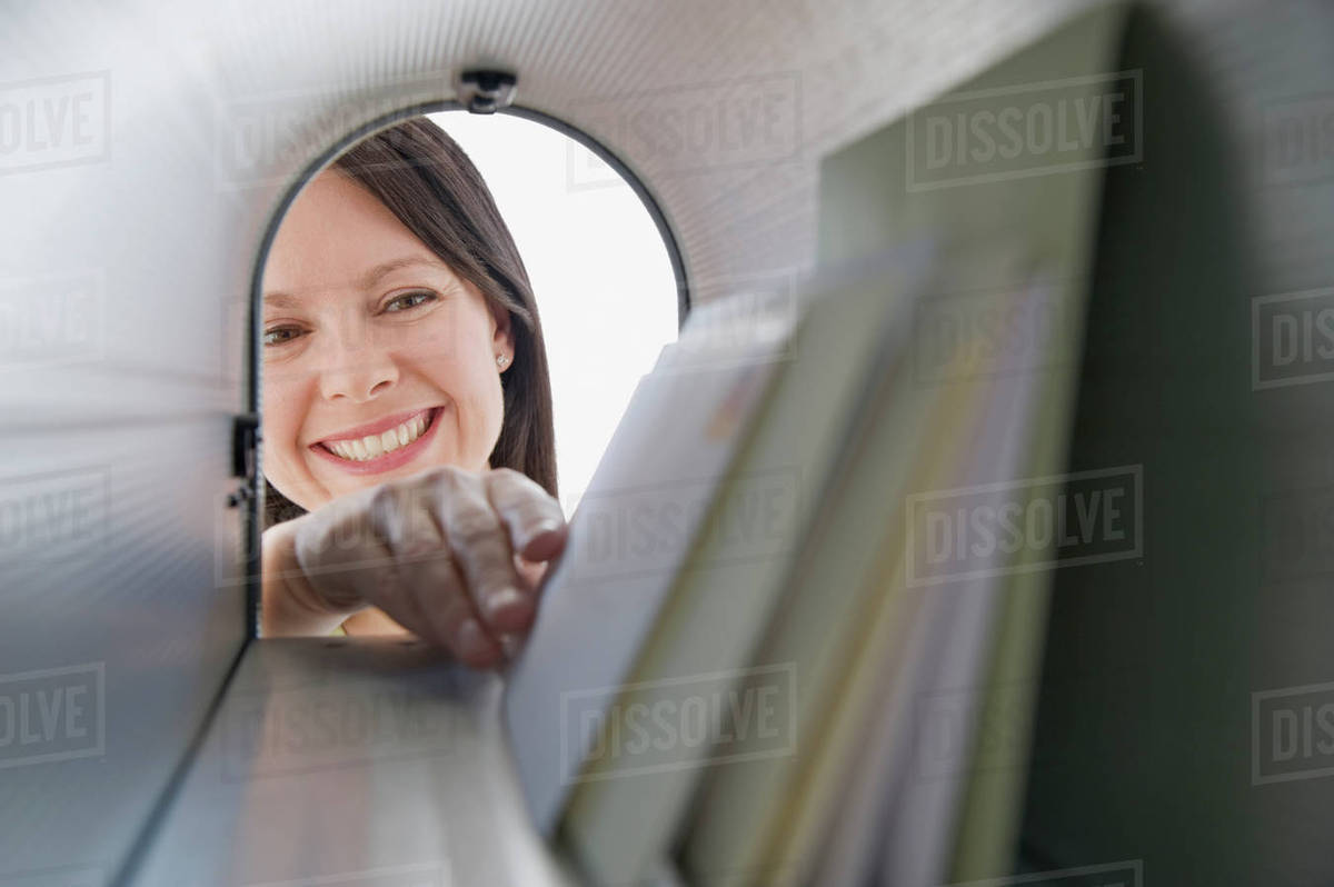 Woman reaching into mailbox for mail - Stock Photo - Dissolve