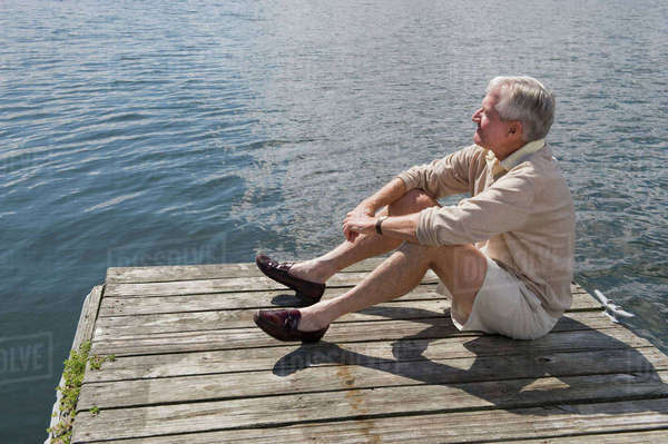 Senior man sitting on dock - Royalty-free Stock Photo | Dissolve