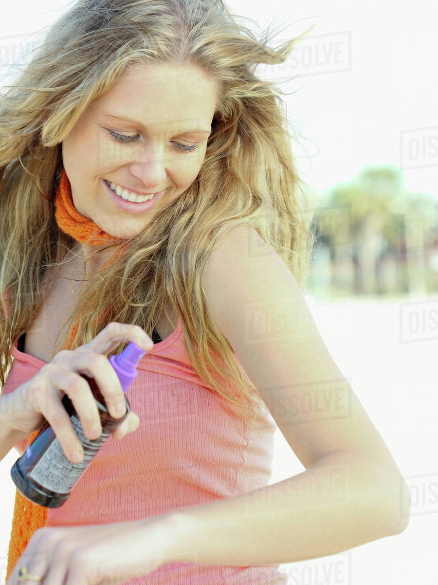 Woman spraying on sunscreen - Royalty-free Stock Photo | Dissolve