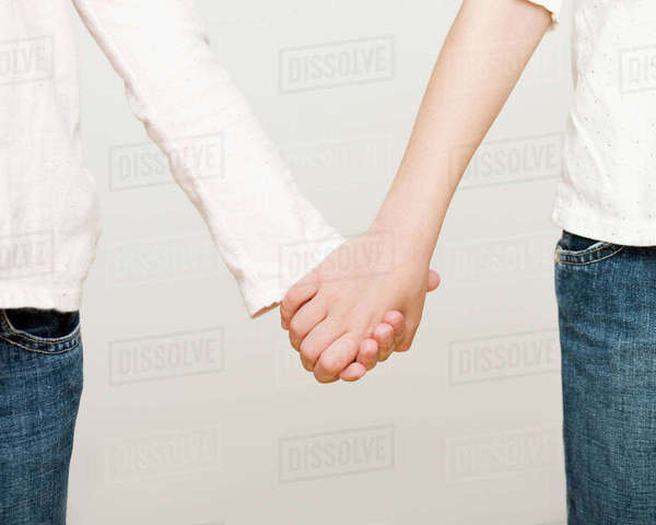 Two girls holding hands - Stock Photo - Dissolve