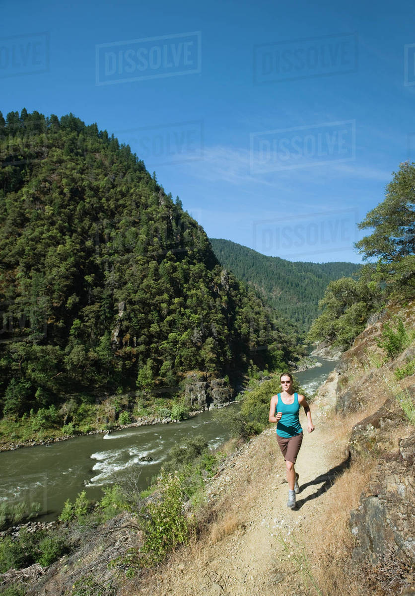 Woman running on riverside trail - Royalty-free Stock Photo | Dissolve