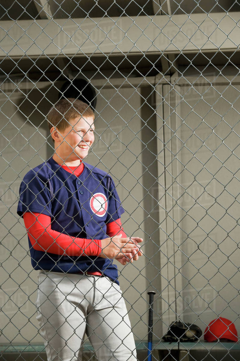 Baseball player standing in dugout - Stock Photo - Dissolve