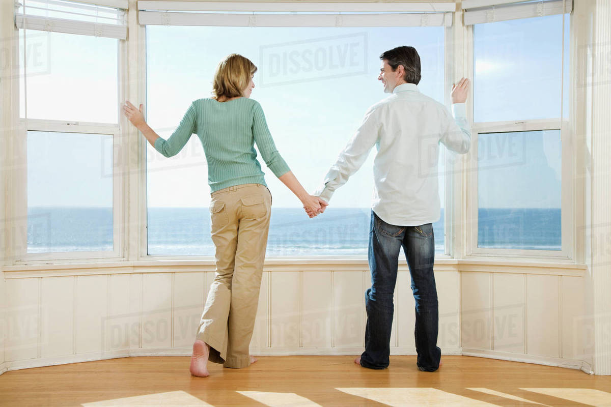 Couple holding hands next to window - Stock Photo - Dissolve