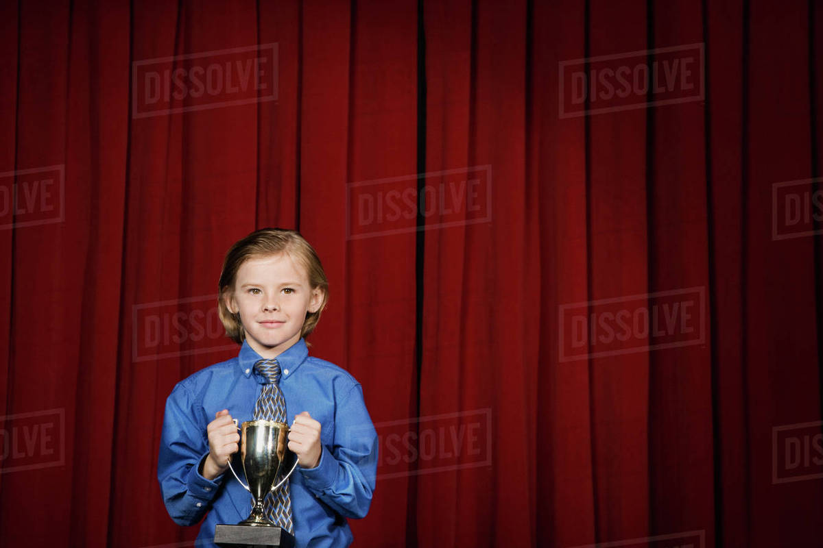 Boy holding trophy on stage - Royalty-free Stock Photo | Dissolve