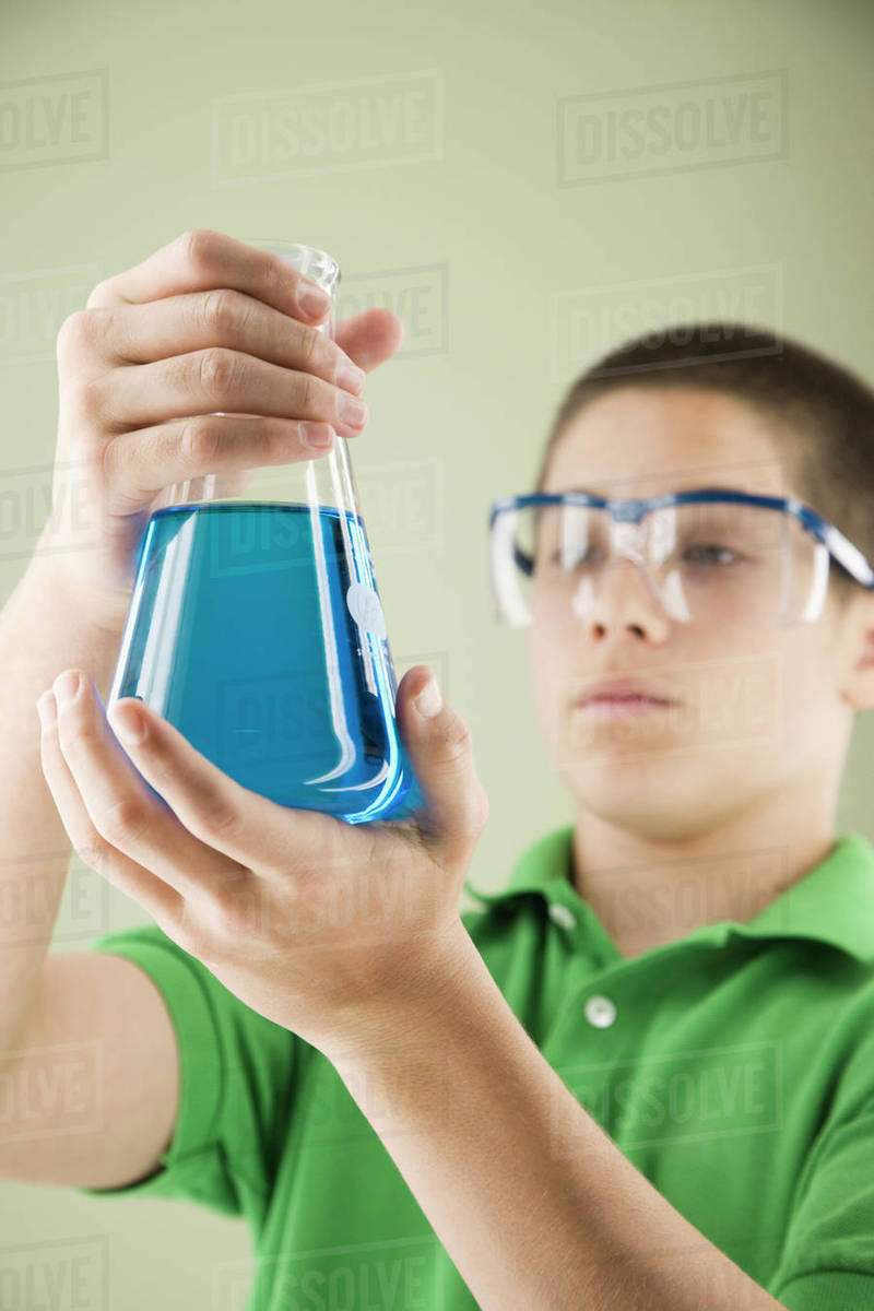 Boy looking at beaker of liquid - Royalty-free Stock Photo | Dissolve