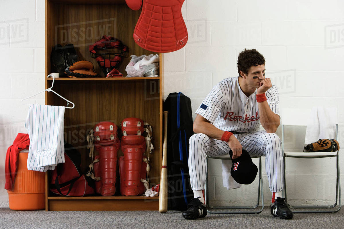Baseball player sitting in locker room looking pensive - Royalty-free ...