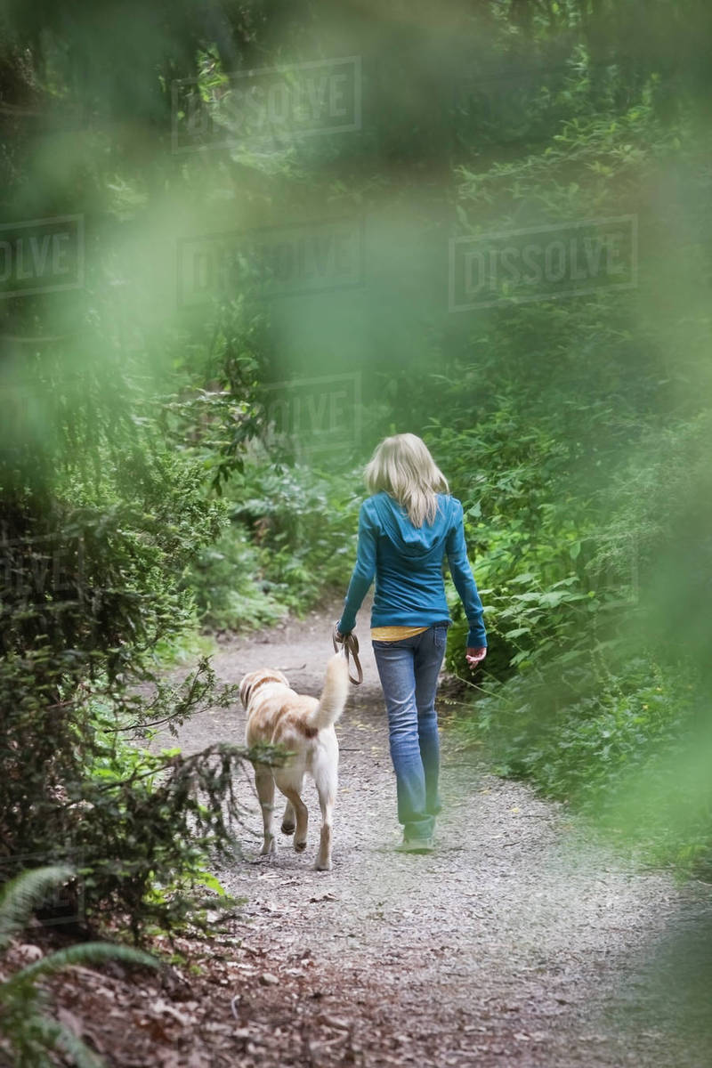 Girl walking dog on forest path - Royalty-free Stock Photo | Dissolve