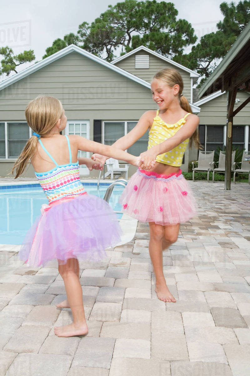 Girls in tutus playing by swimming pool - Stock Photo - Dissolve