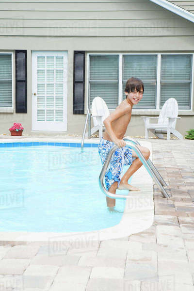 Boy stepping out of swimming pool - Stock Photo - Dissolve