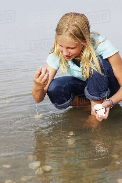 Girl finding seashells in ocean - Royalty-free Stock Photo | Dissolve