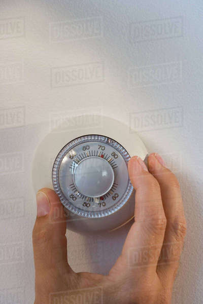 Man adjusting thermostat - Royalty-free Stock Photo | Dissolve