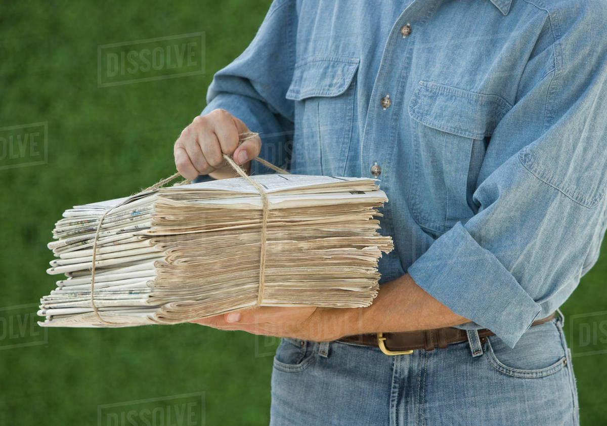 Man carrying bundle of newspapers - Stock Photo - Dissolve