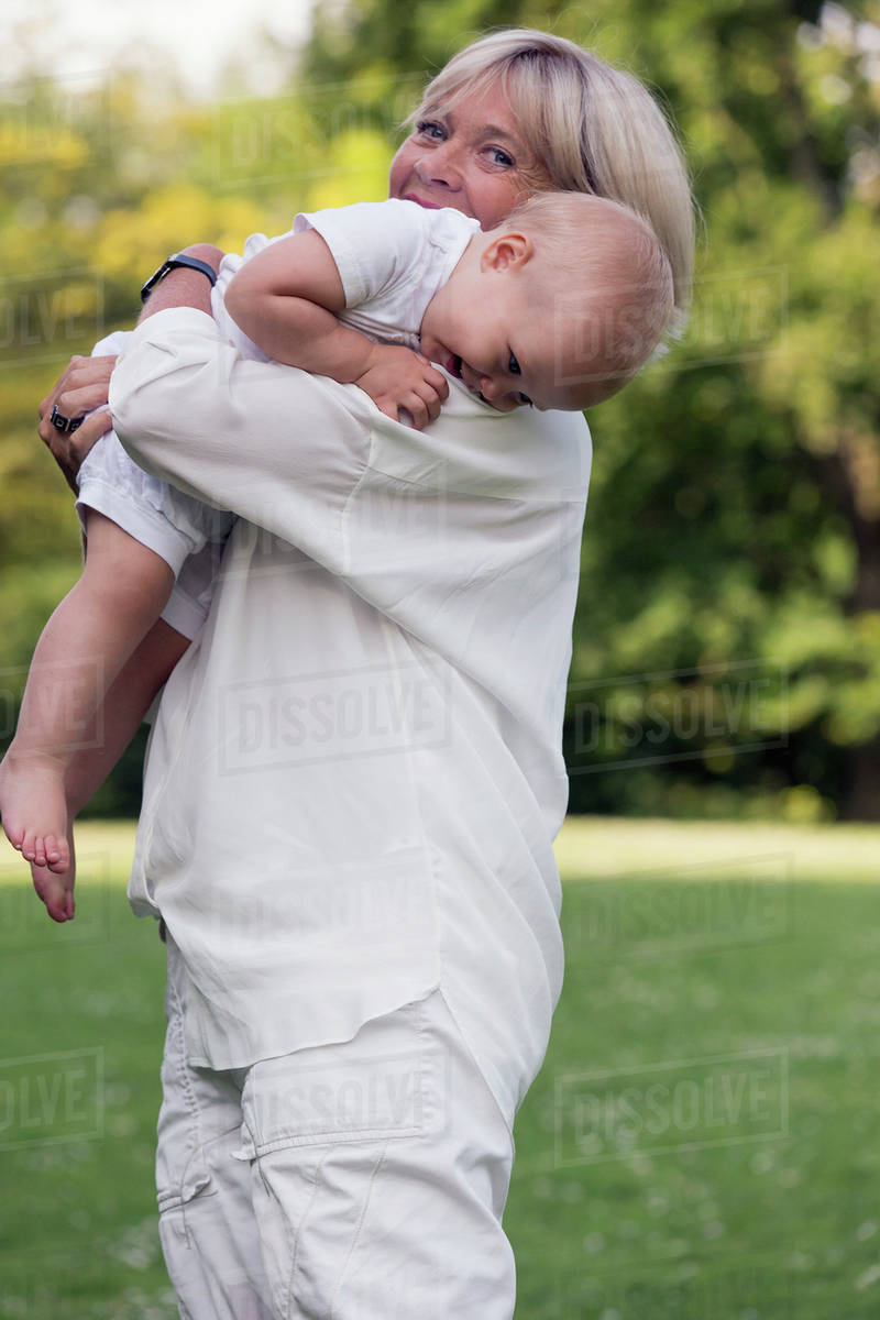 Grandmother carrying her granddaughter (12-17 months) on shoulder ...
